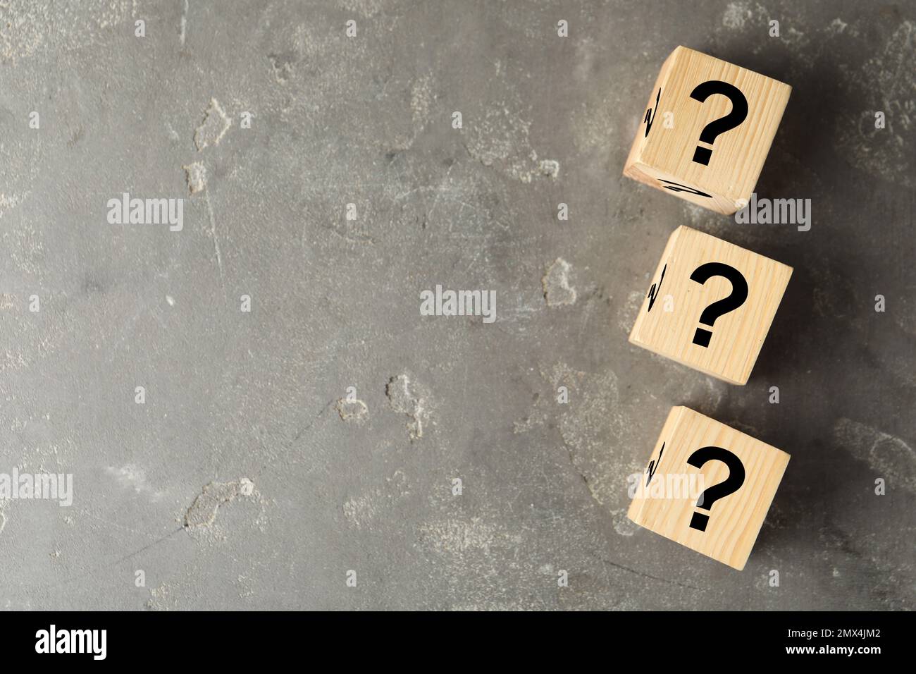 Cubes with question marks on grey stone table, flat lay. Space for text ...