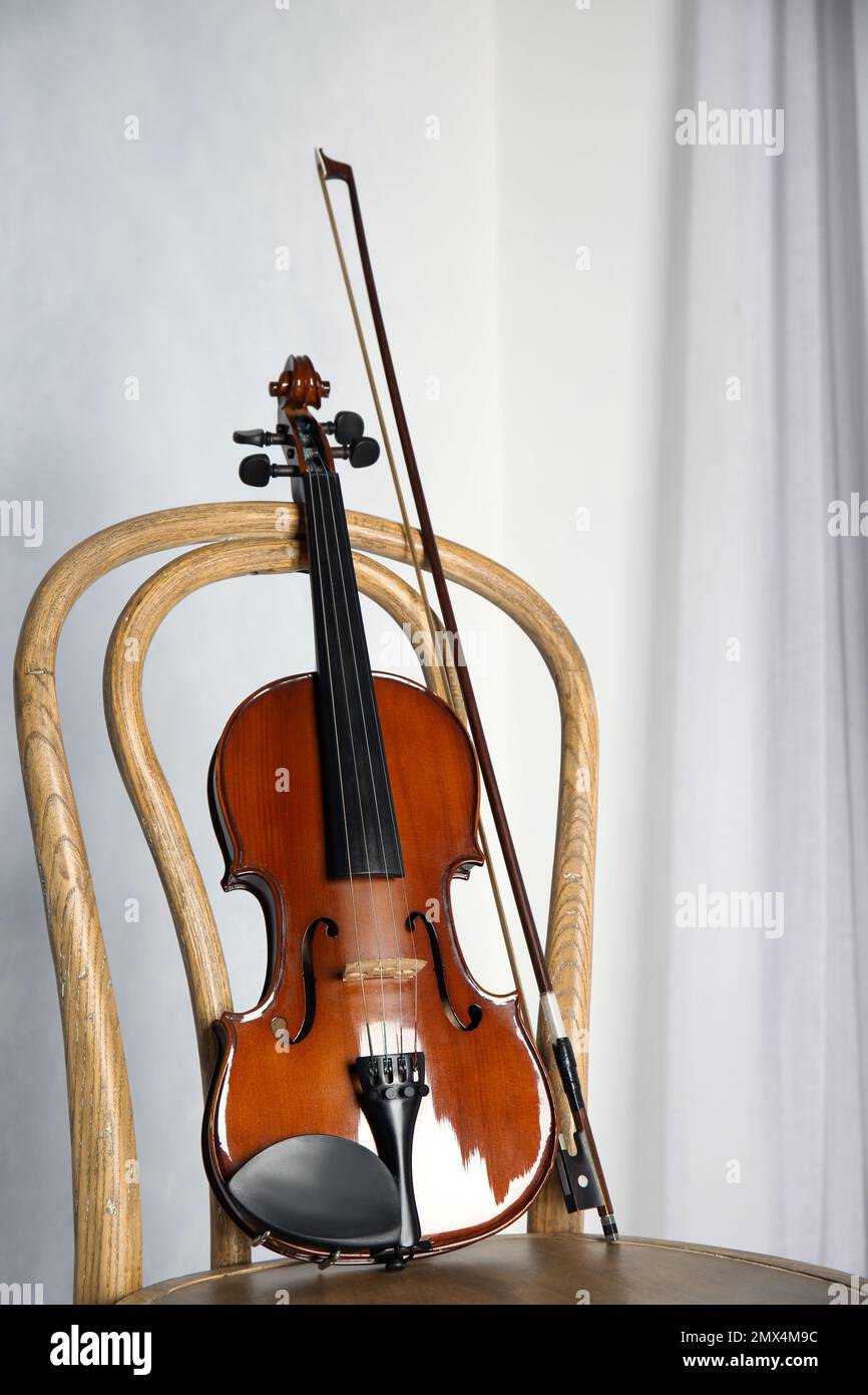 Classic violin and bow on chair near light wall Stock Photo - Alamy