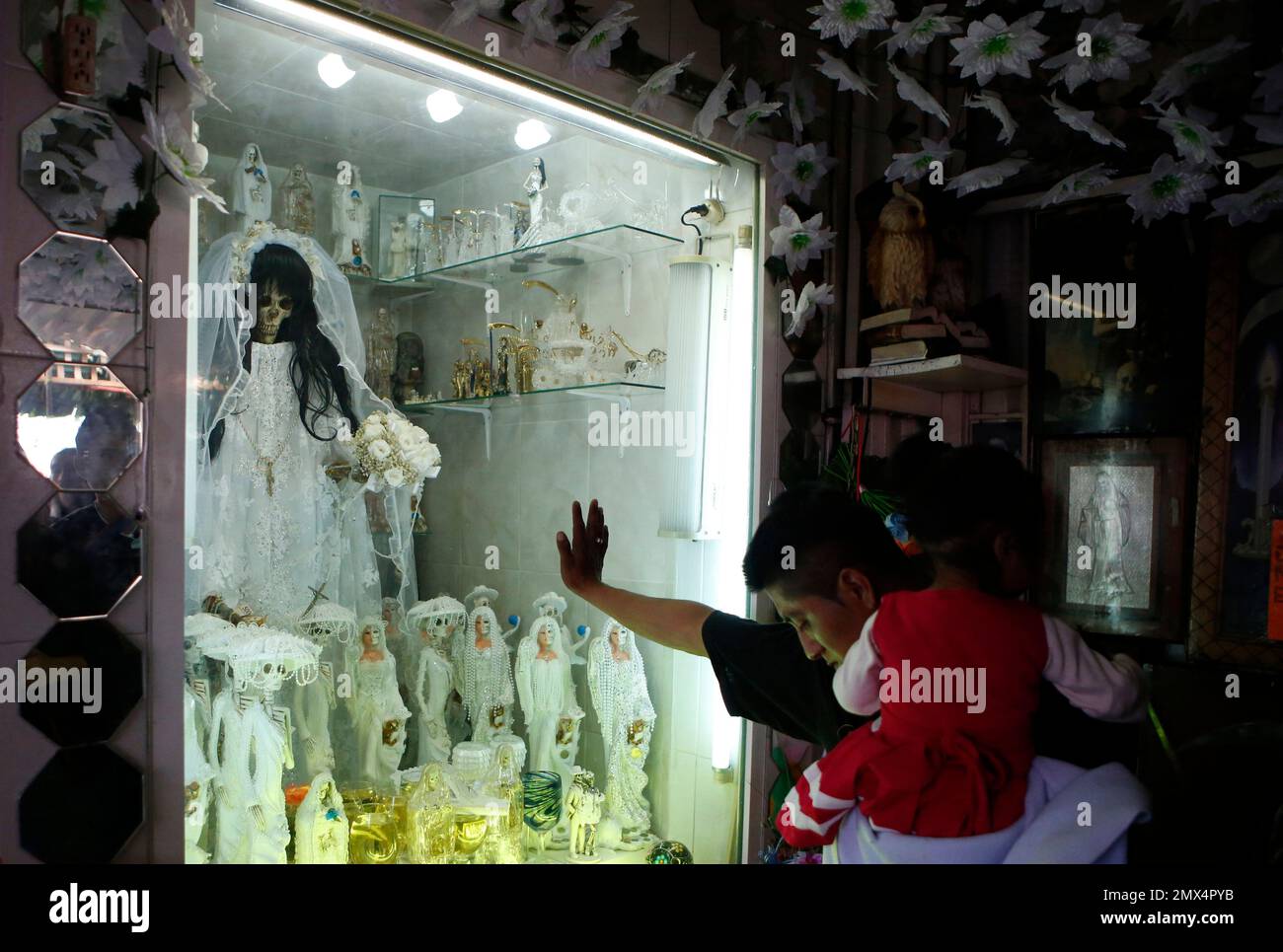 A devotee carrying his daughter rests his hand on the glass as he pays ...