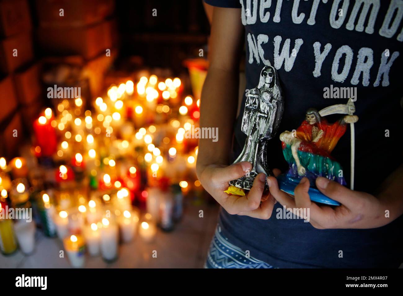 A young girl holds figurines representing La Santa Muerte, or Saint ...