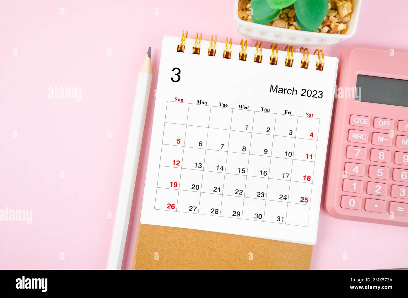 March 2023 desk calendar for 2023 year with calculator on pink color ...