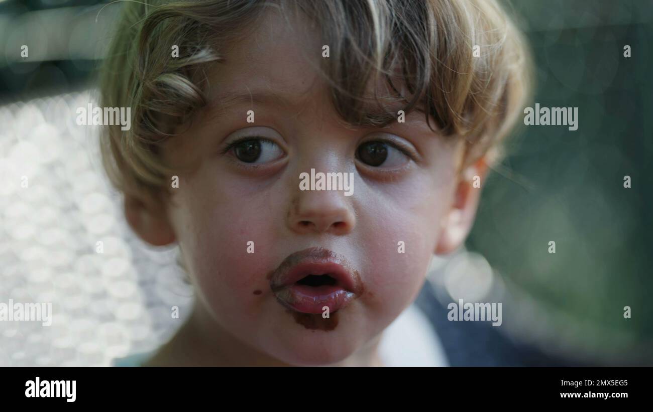 Adorable child boy with dirty mouth covered with chocolate ice cream ...