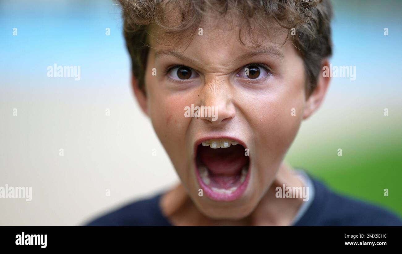 One angry young boy screaming to camera. Preteen child open mouth ...