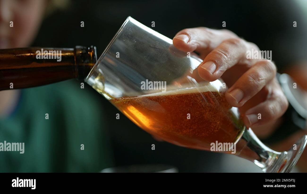 Closeup hand serving beer into glass. Man pouring alcoholic beverage ...