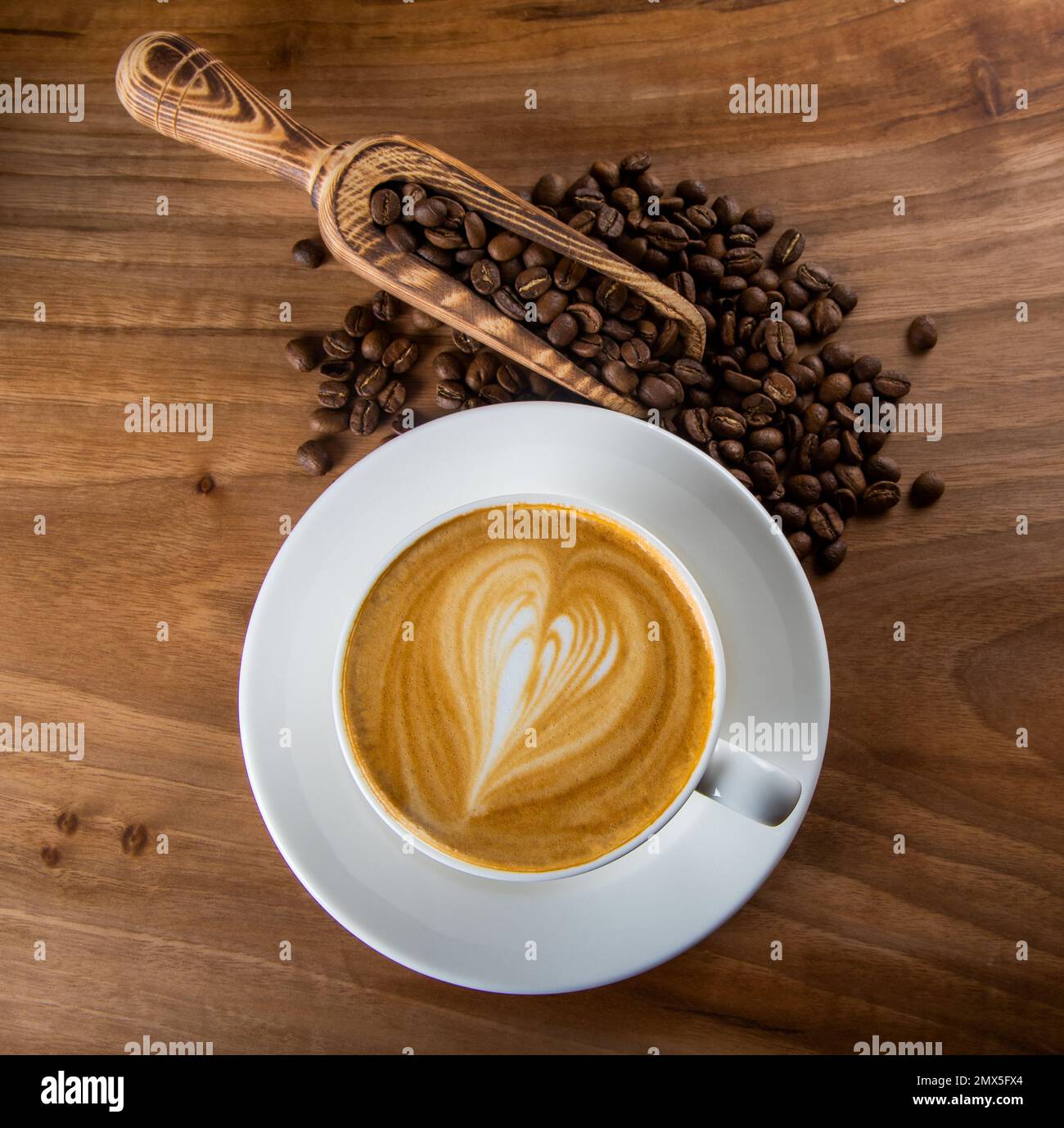 Roasted coffee beans with latte with heart foam pattern Stock Photo - Alamy