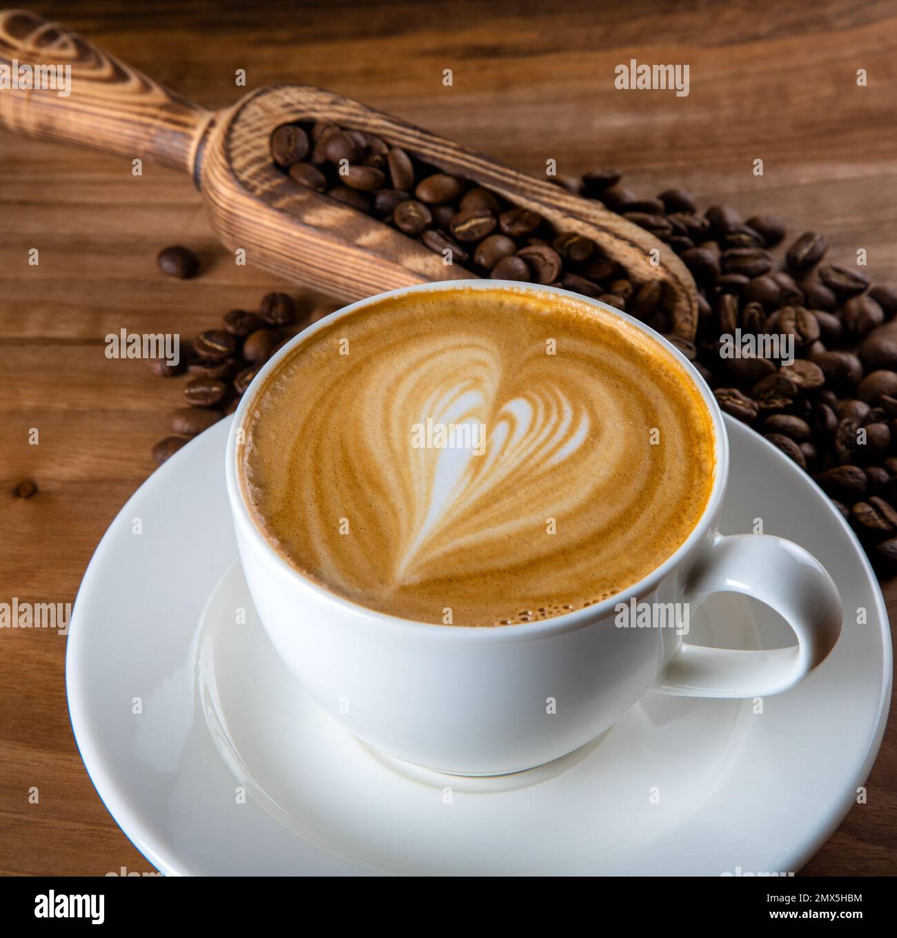 Roasted coffee beans with latte with heart foam pattern Stock Photo - Alamy