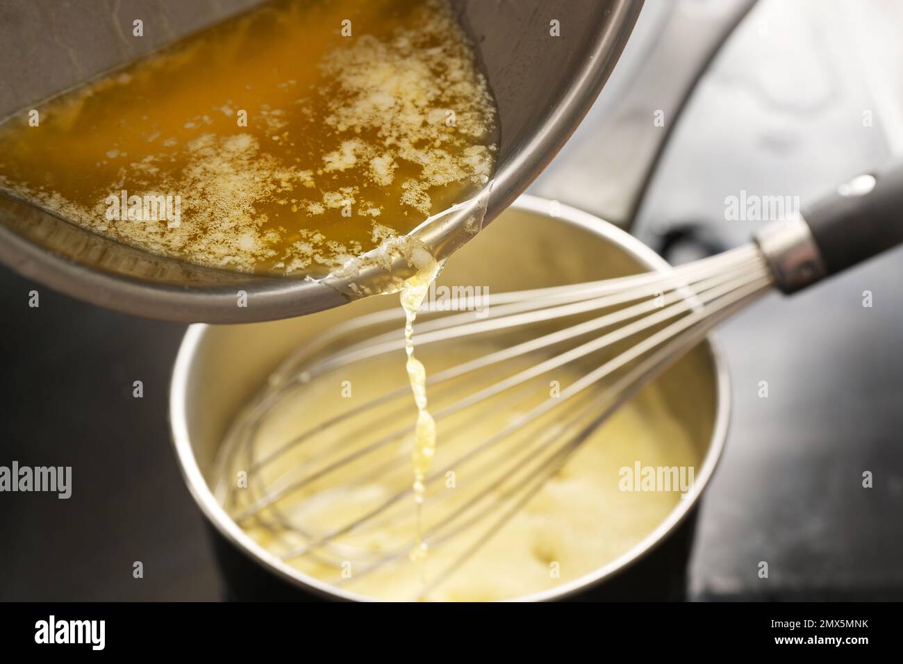 Cooking process of hollandaise sauce, pouring melted butter into the ...