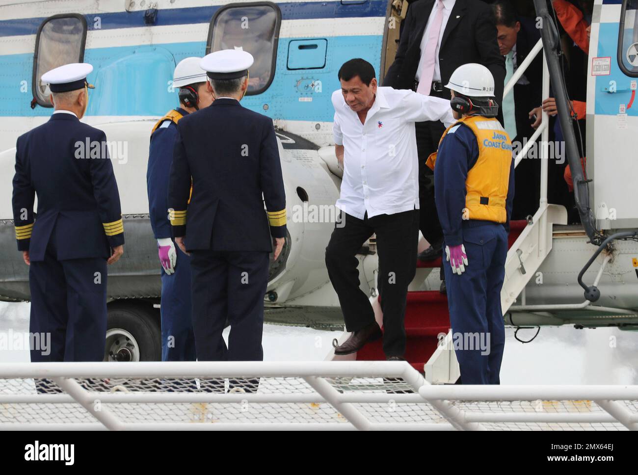 Philippine President Rodrigo Duterte, center in white outfit, gets off ...