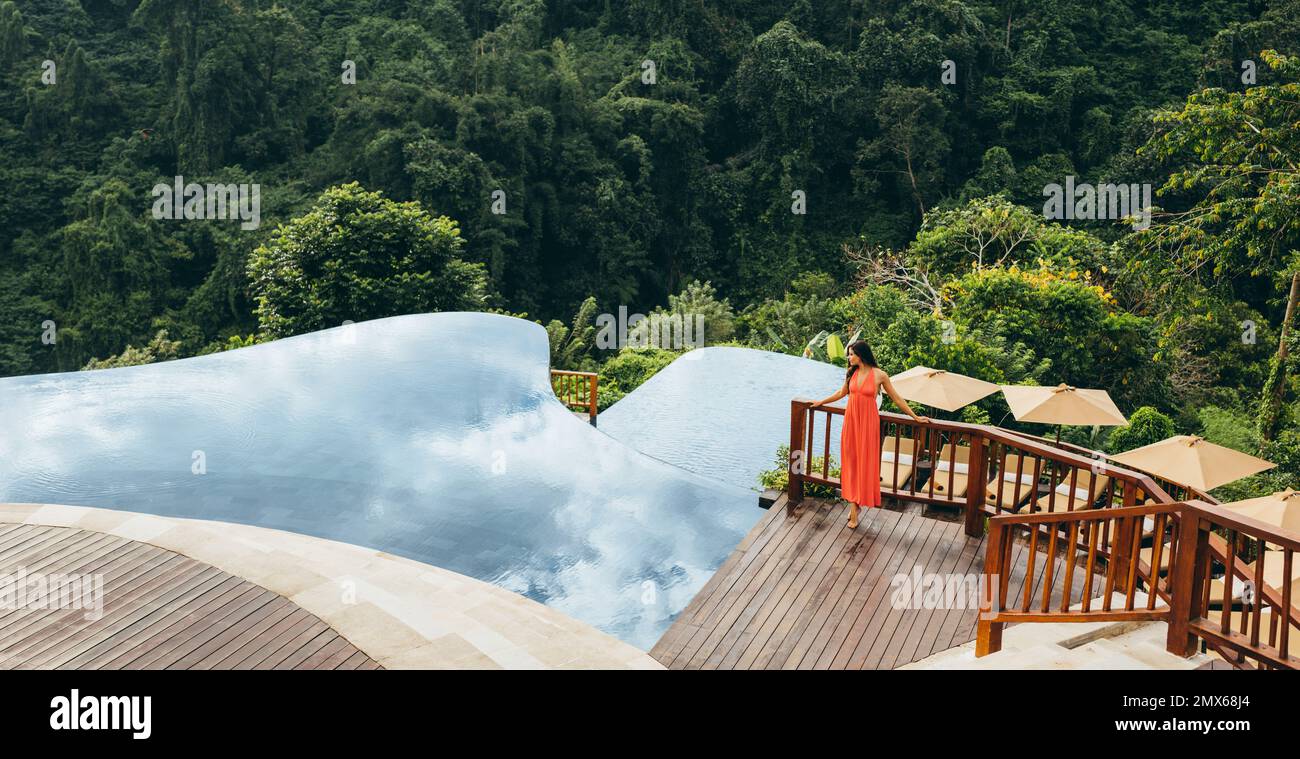 Shot of relaxed young female standing near poolside of luxury resort ...