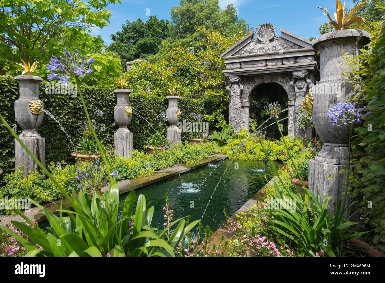 A pool with Alchemilla Mollis and a shell grotto pavillionand water ...