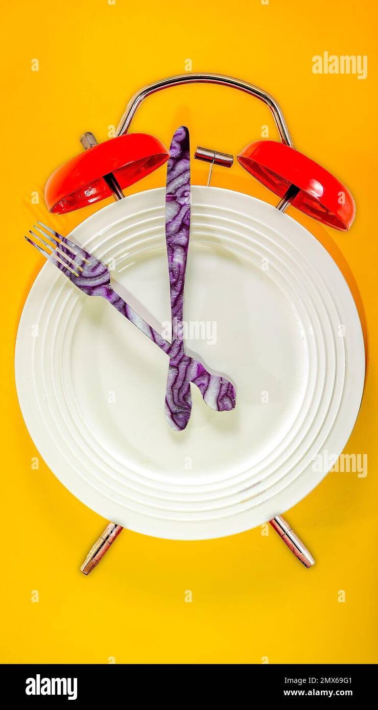 Plate like a clock with fork and knife from red cabbage on yellow ...