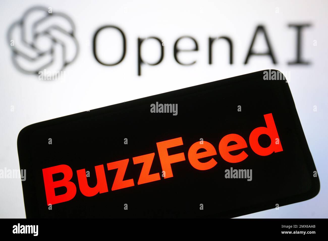 In this photo illustration, BuzzFeed logo is seen on a smartphone screen and OpenAI logo on pc ...