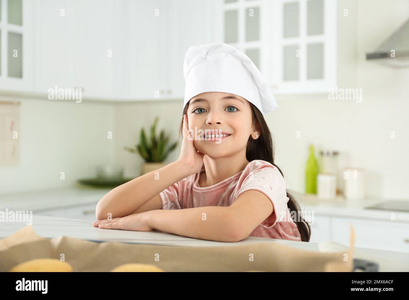 Cute little girl wearing chef hat in kitchen Stock Photo - Alamy