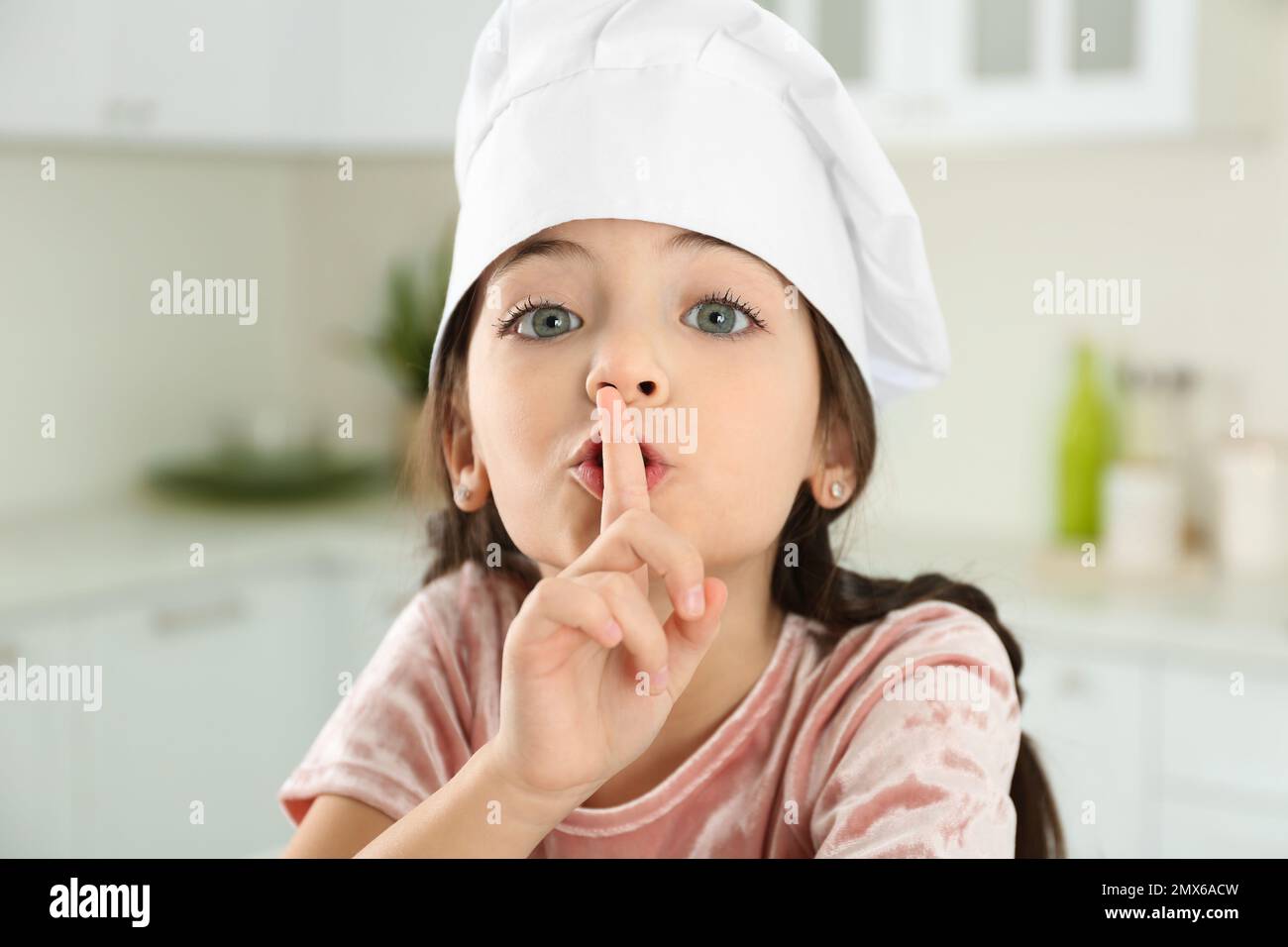 Cute little girl wearing chef hat in kitchen Stock Photo - Alamy