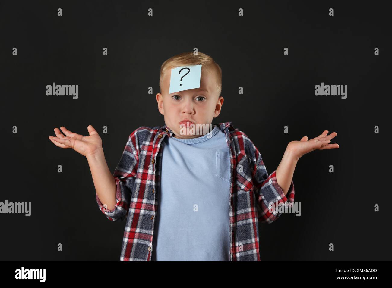 Confused boy with question mark sticker on forehead against black ...