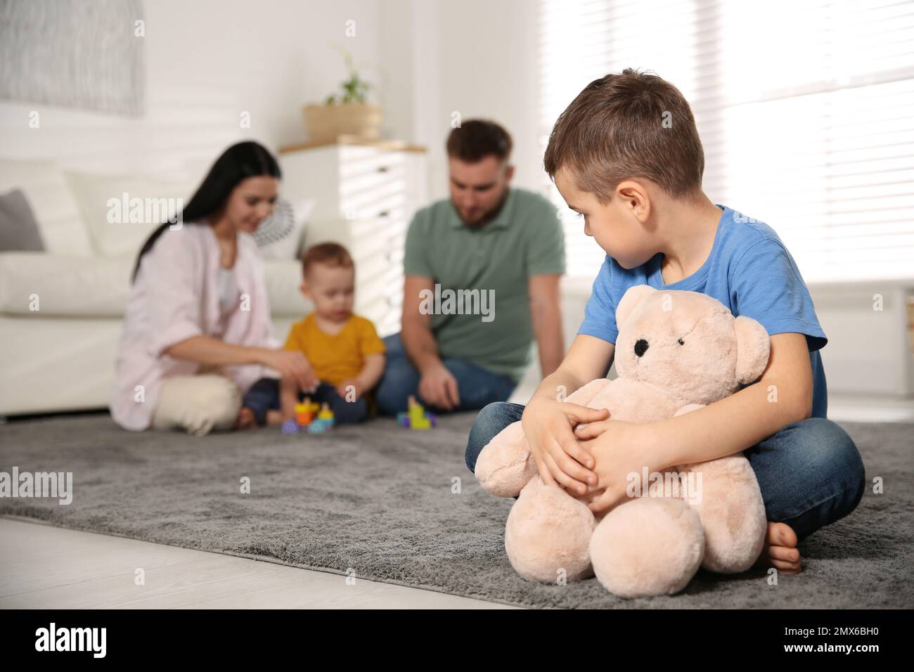 Unhappy little boy feeling jealous while parents spending time with his ...