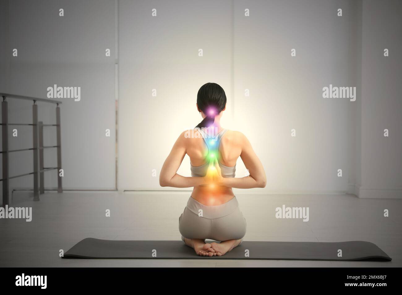 Young woman with chakra points practicing yoga in studio, back view. Healing energy Stock Photo ...
