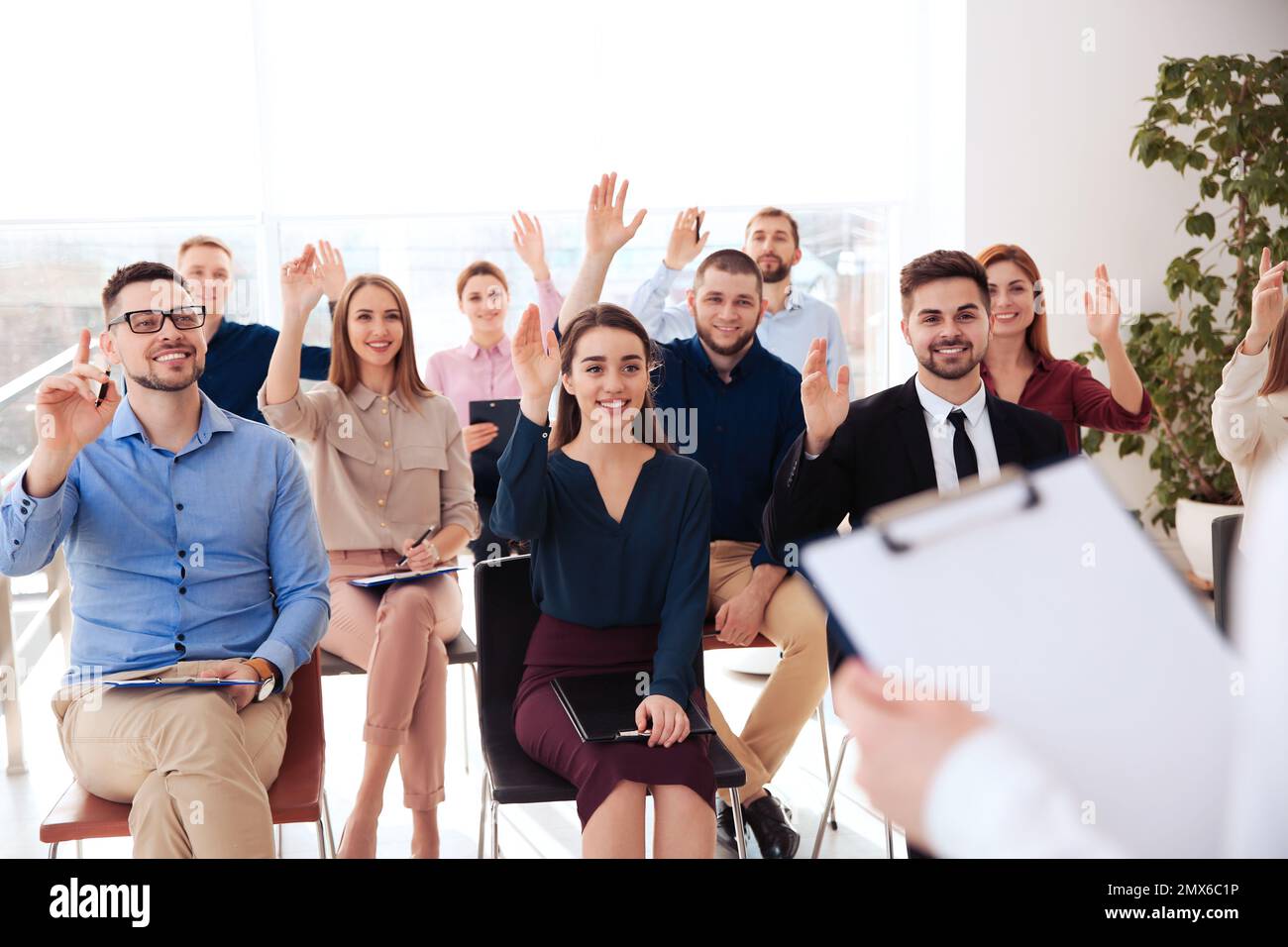 People raising hands to ask questions at business training indoors ...