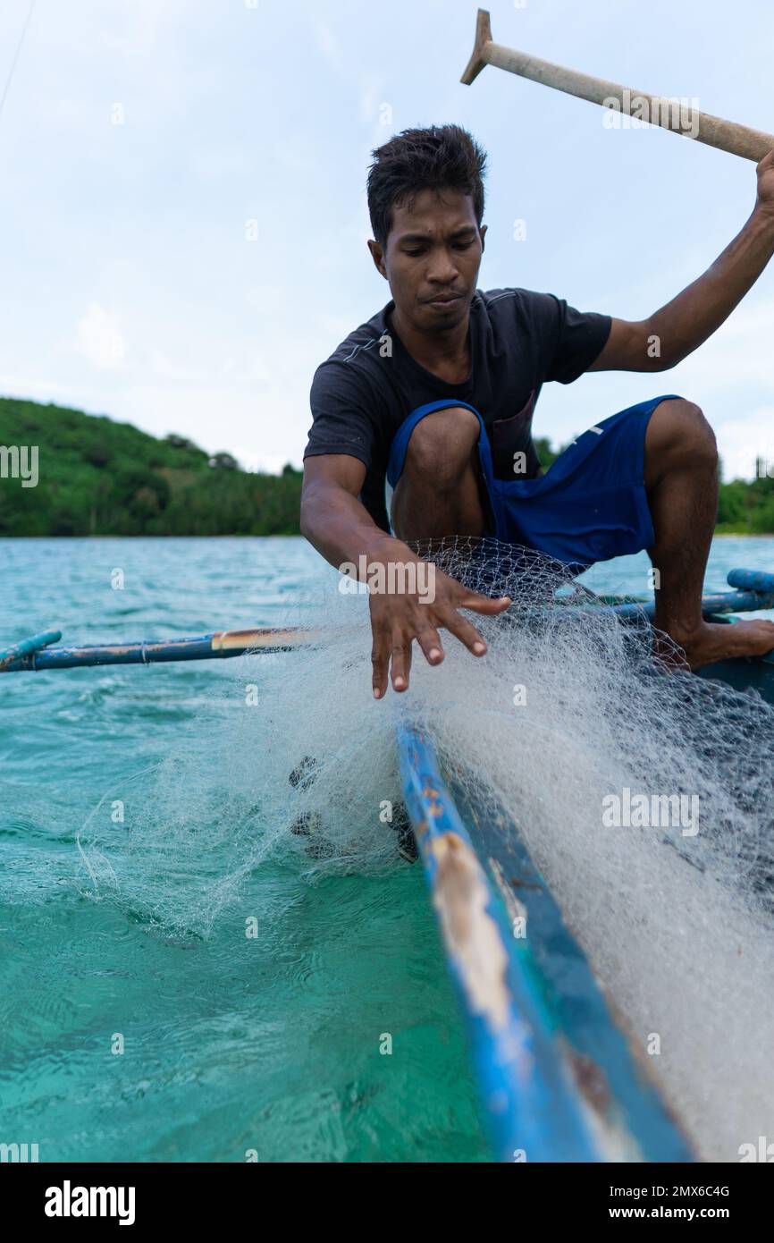 young filipino fisherman leaving his fishing net at sea, real people ...