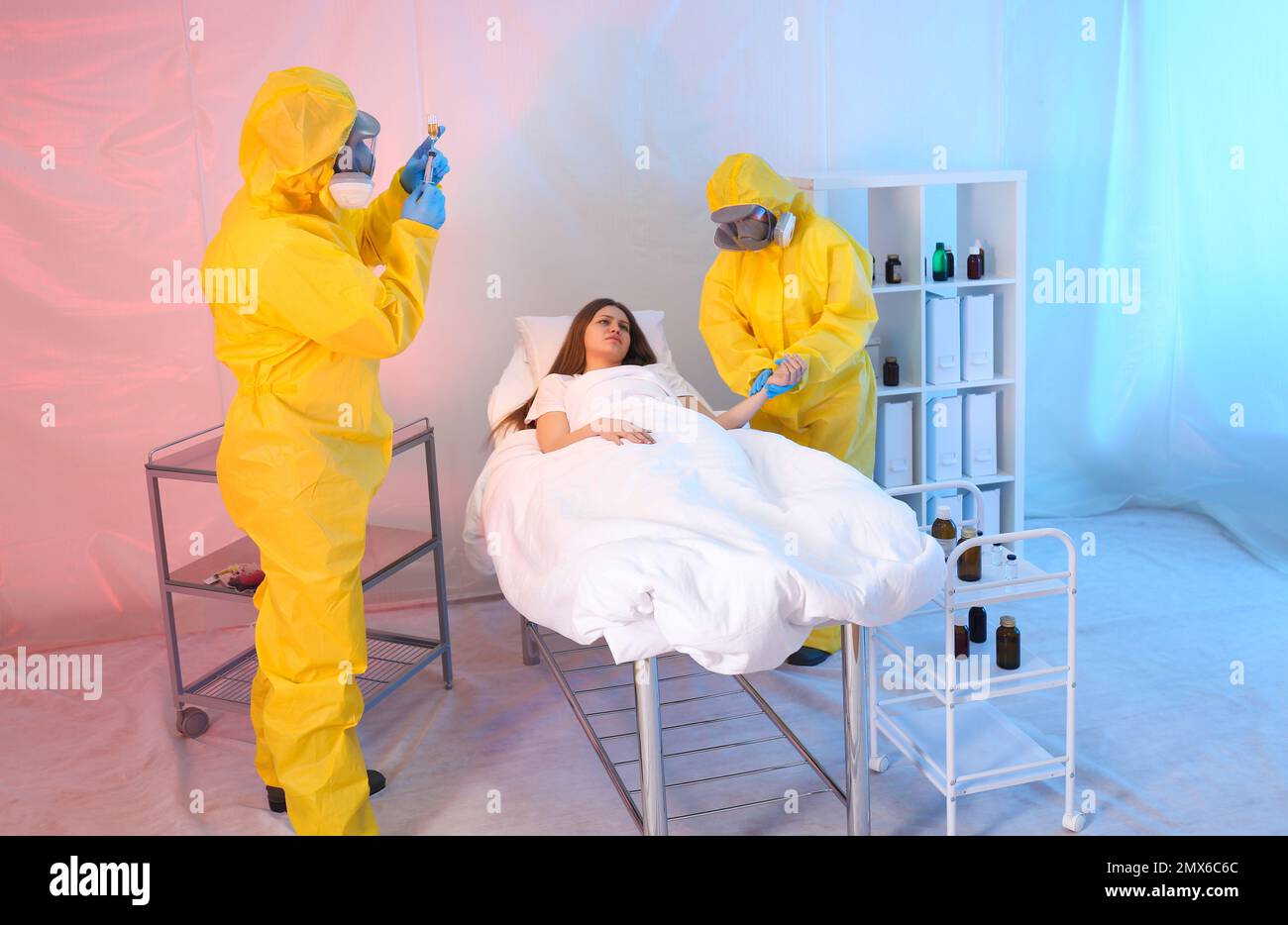 Paramedics wearing protective suits examining patient with virus in ...