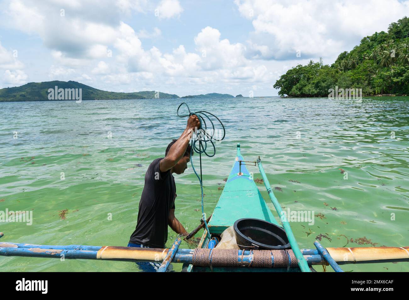young Filipino fisherman picking up the anchor to go fishing ...