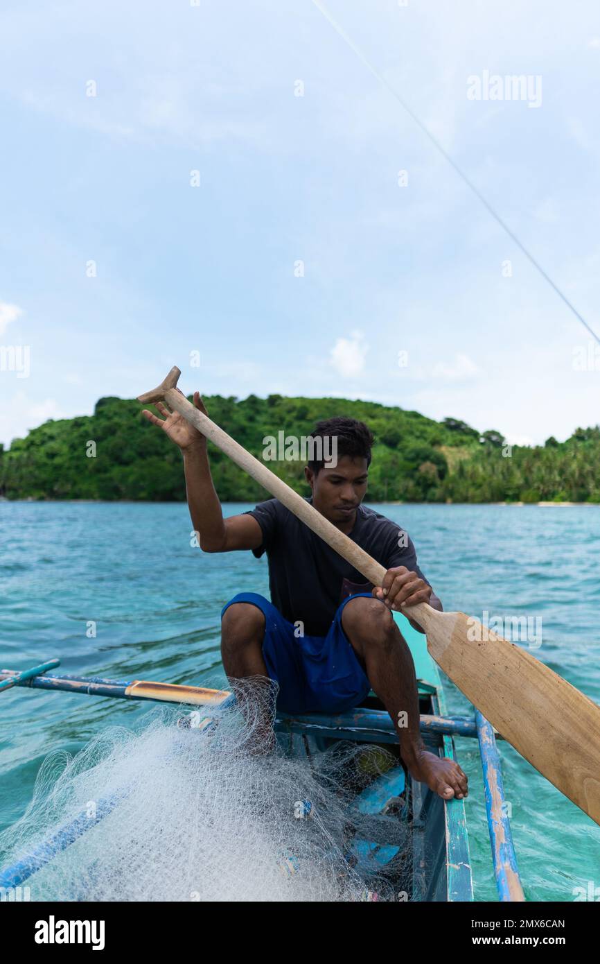 vertical photo Filipino fisherman rows on a small boat going fishing ...