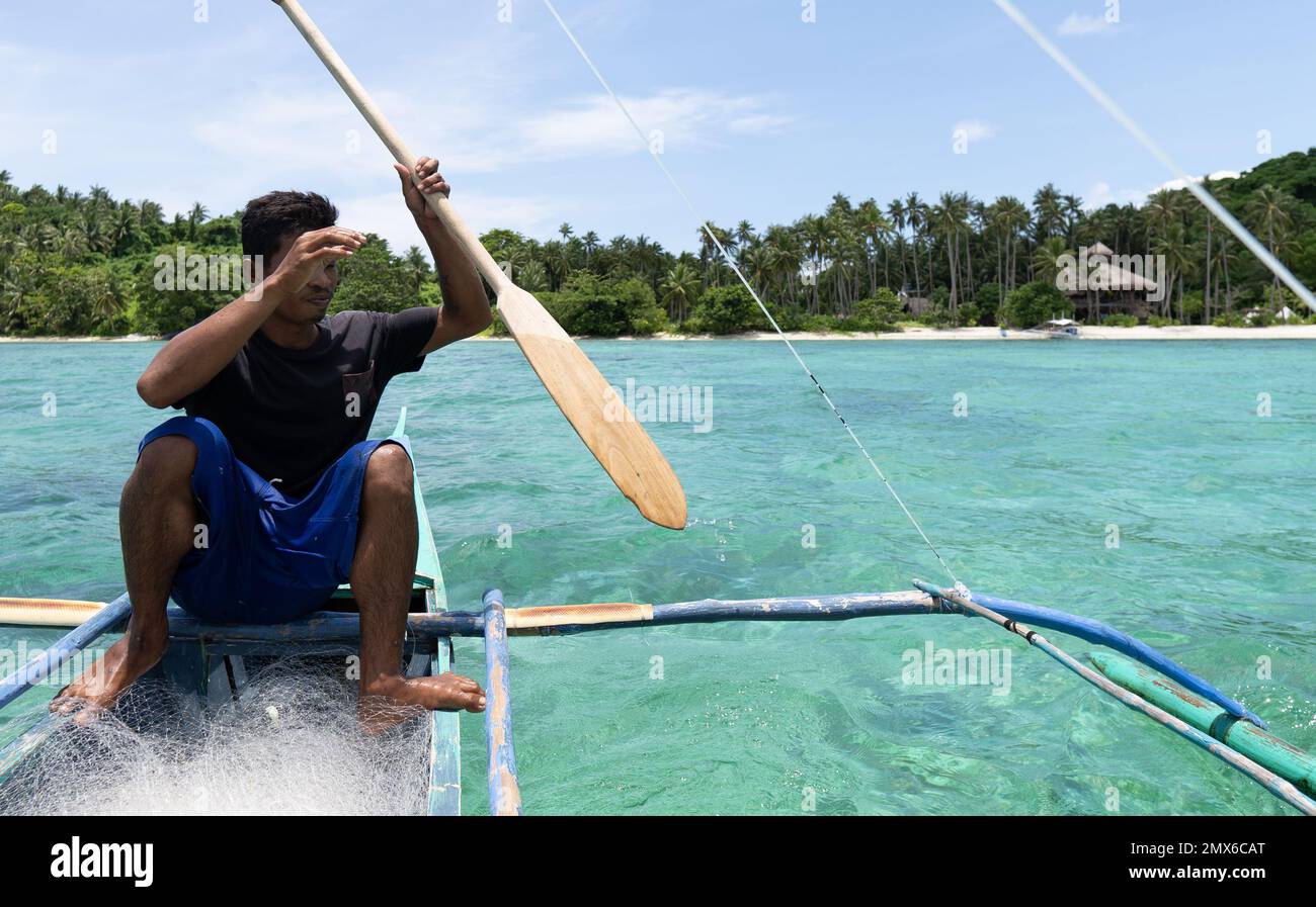 Filipino fisherman rows on a small boat going fishing with his fishing ...