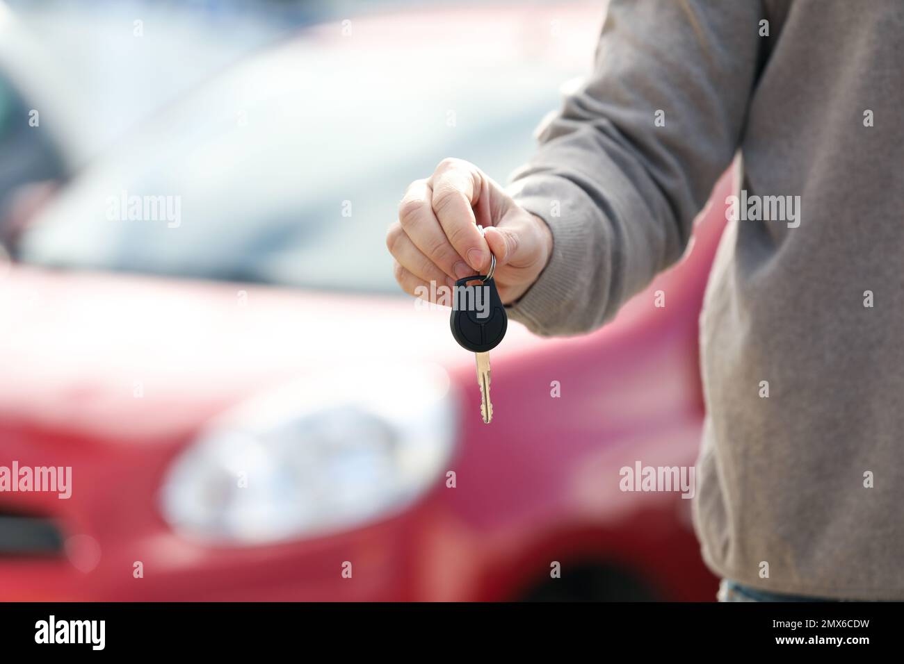 Man holding key in modern auto dealership, closeup. Buying new car ...