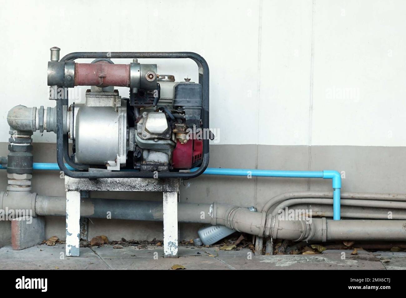 A suite of a small fire pump on a wall fence Stock Photo - Alamy