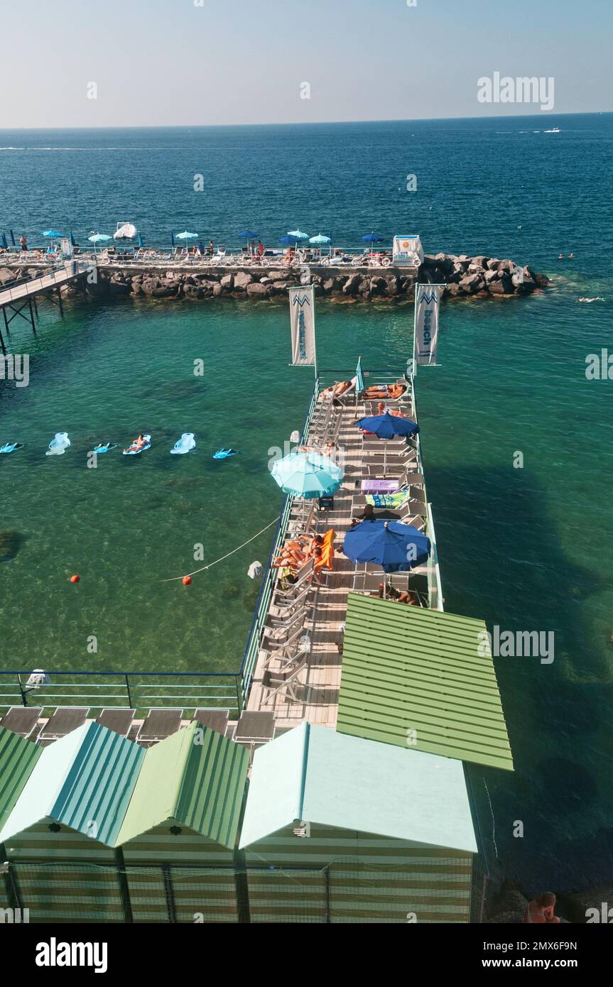 An aerial view of sunbathers and sunbeds with colourful parasols next ...