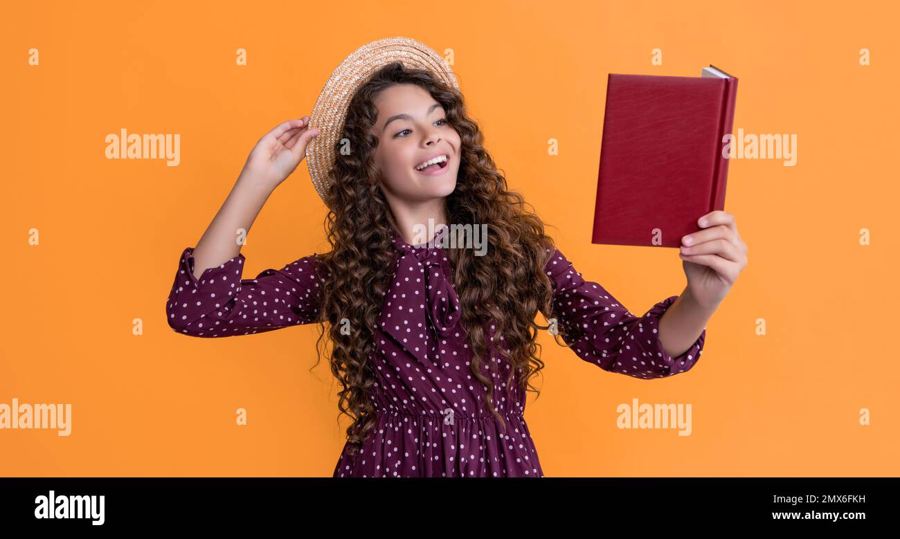 cheerful child with frizz hair recite book on yellow background Stock ...