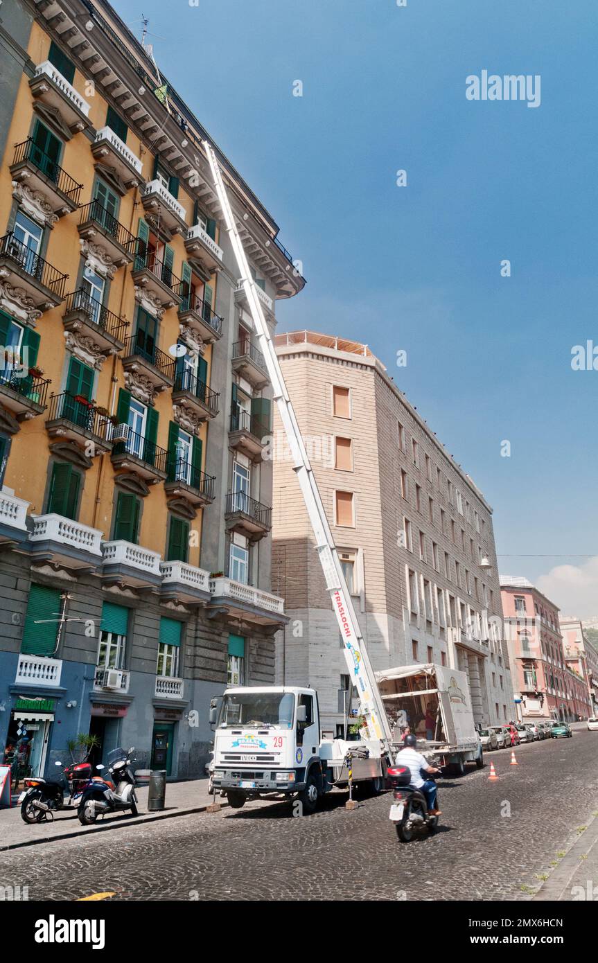A lorry mounted crane hoist delivering goods to a top floor flat in ...