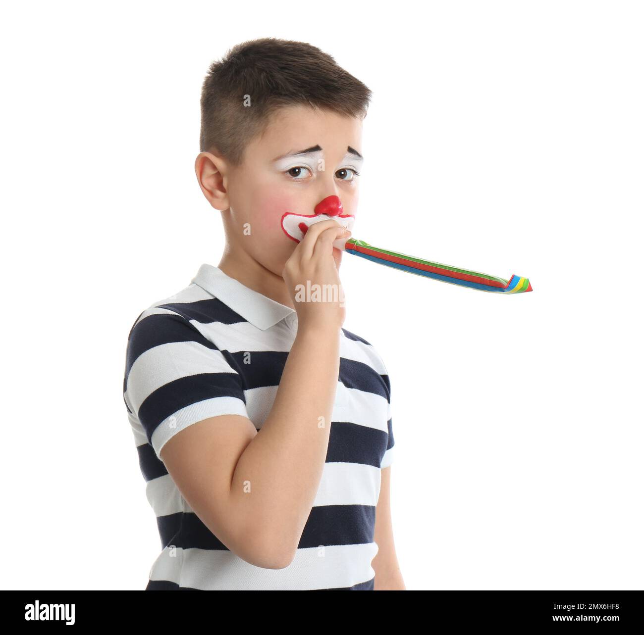 Preteen boy with clown makeup and party horn on white background. April ...