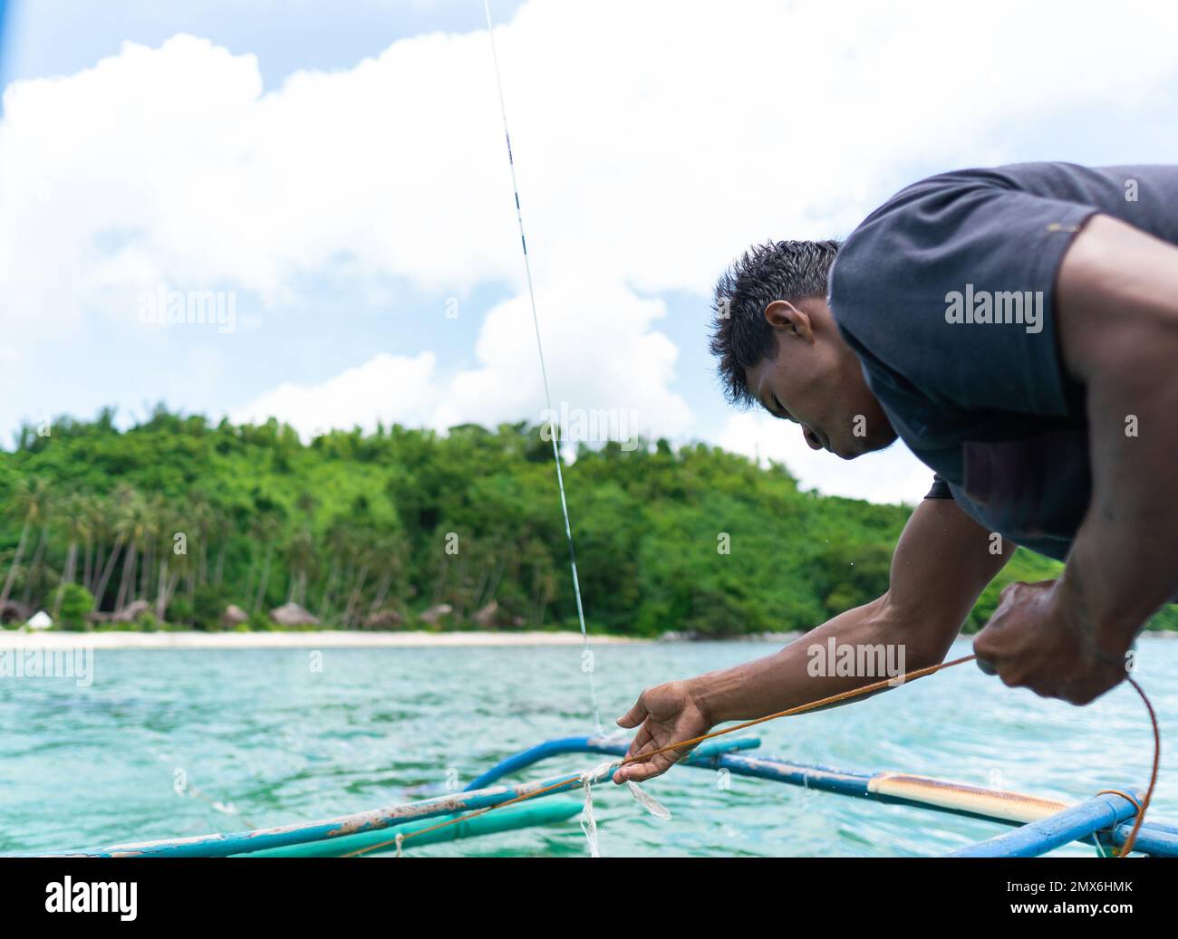 closeup of asian fisherman picking up his fishing net on a small boat ...