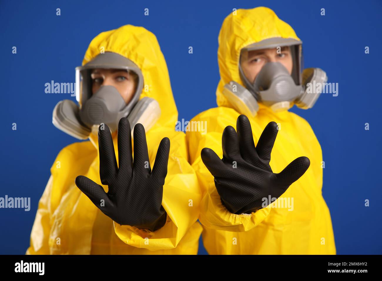 Man and woman in chemical protective suits making stop gesture against ...