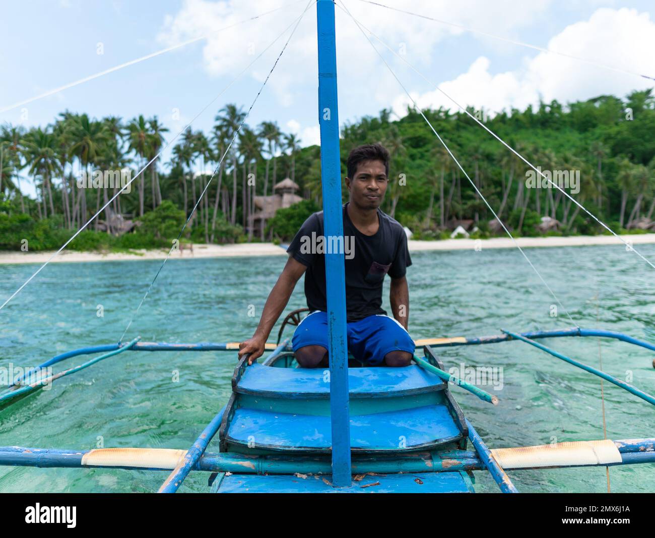 Close-up of young asian fisherman sitting on his boat while watching at ...