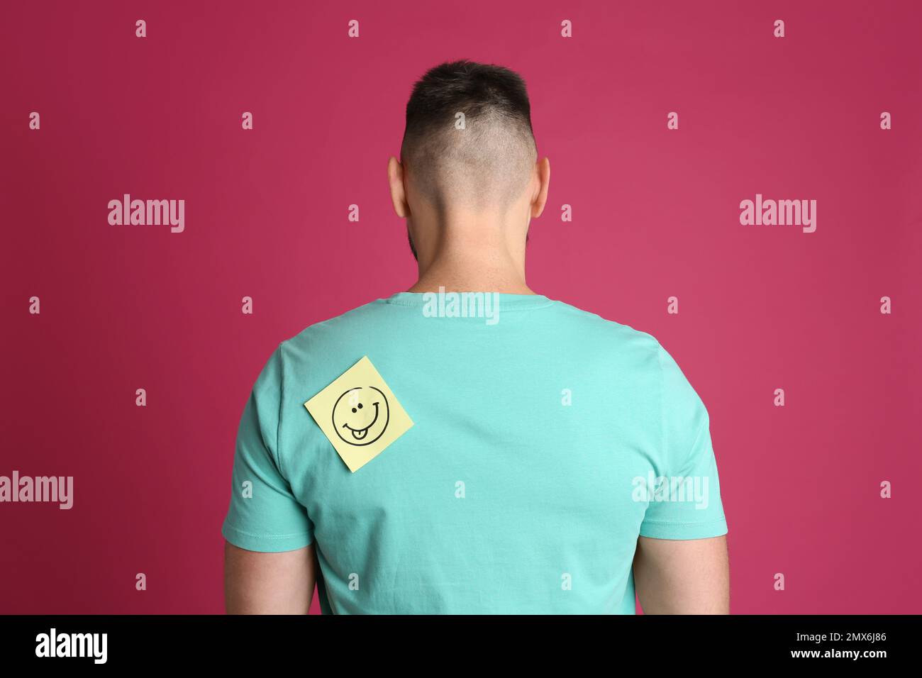 Man with smiling face sticker on back against pink background. April ...