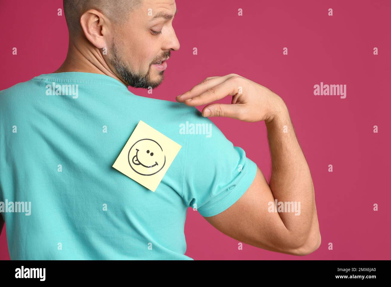 Man with smiling face sticker on back against pink background. April ...