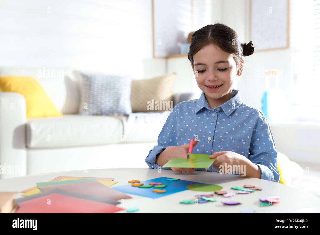 Little girl making greeting card at table indoors, space for text ...