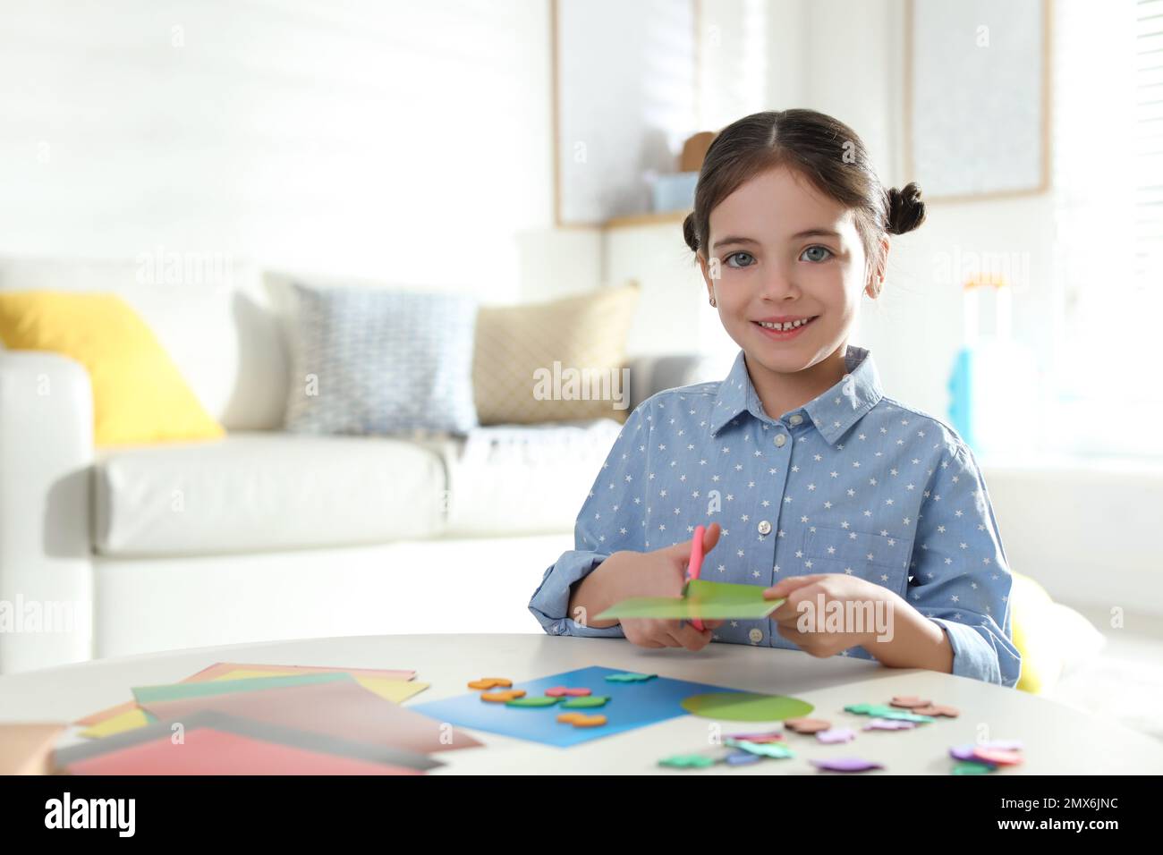 Little girl making greeting card at table indoors, space for text ...