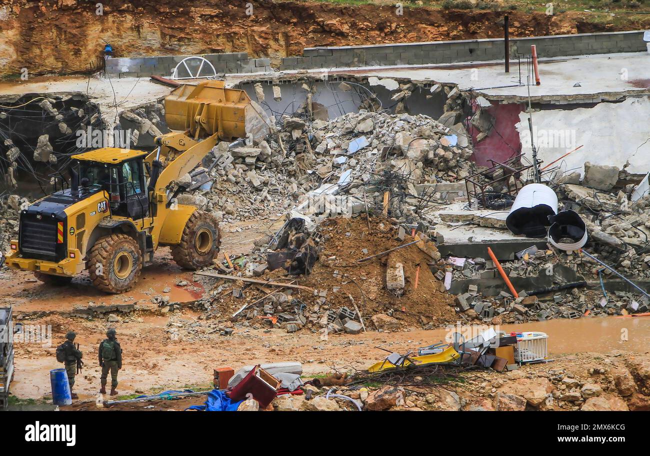 An Israeli military bulldozer, guarded by soldiers, is seen demolishing ...