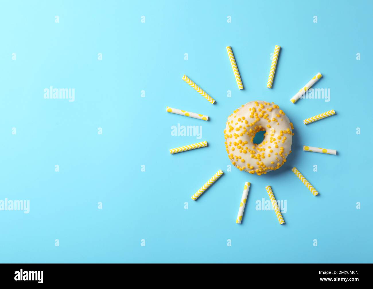Sun made with donut and straws on light blue background, flat lay ...