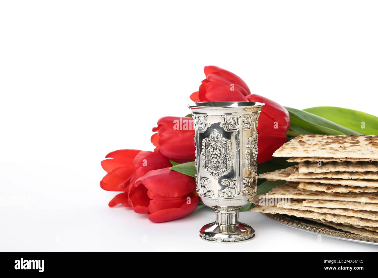 Passover matzos, silver goblet and flowers on white background. Pesach ...