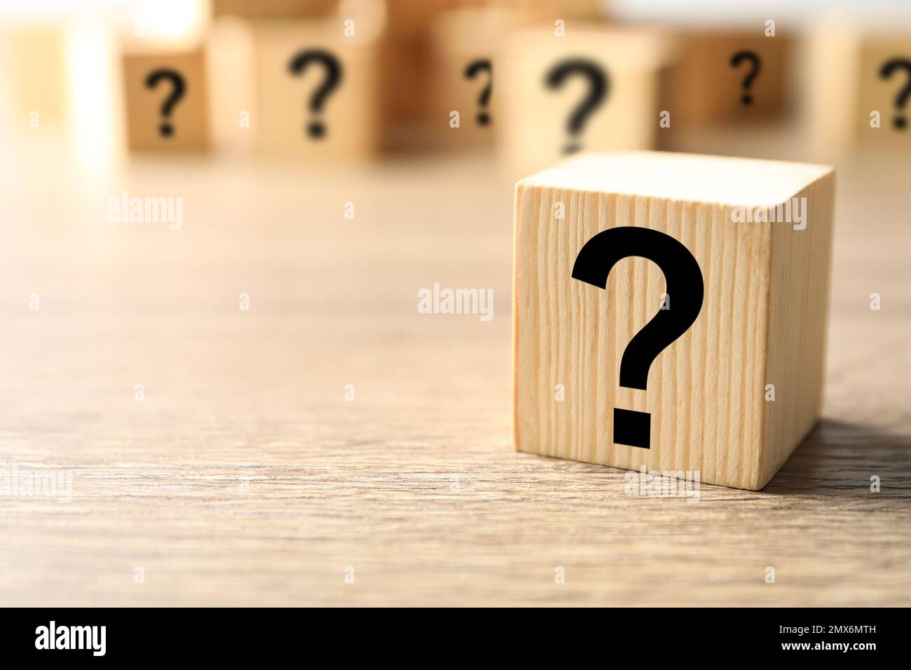 Cube with question mark on wooden background, closeup. Space for text ...