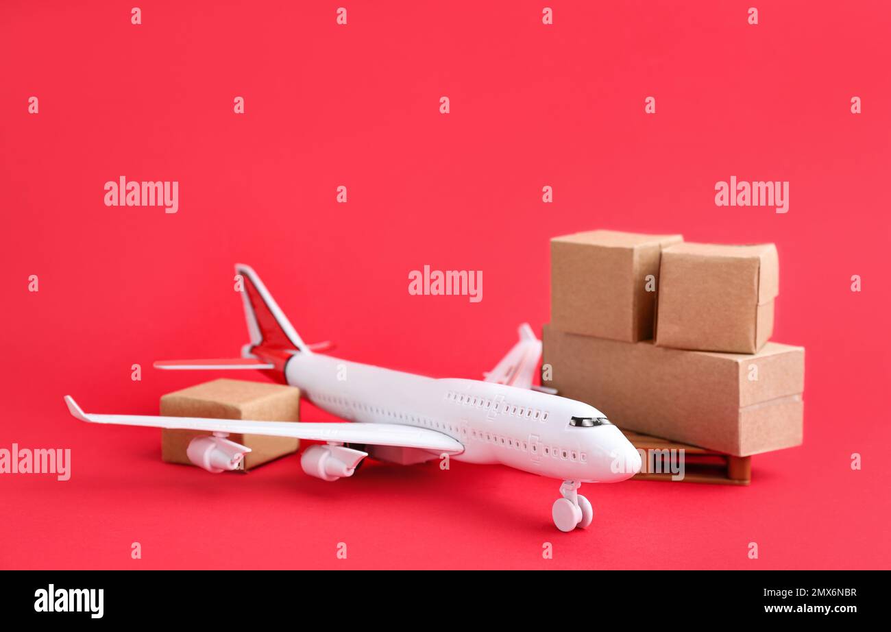 Airplane model and carton boxes on red background. Courier service ...