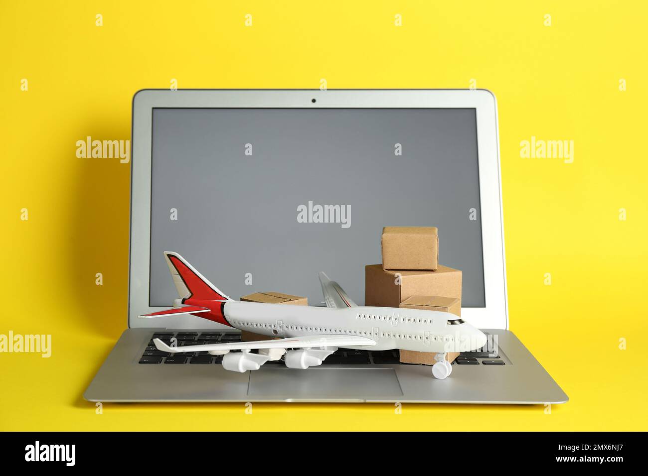 Laptop, airplane model and carton boxes on yellow background. Courier ...