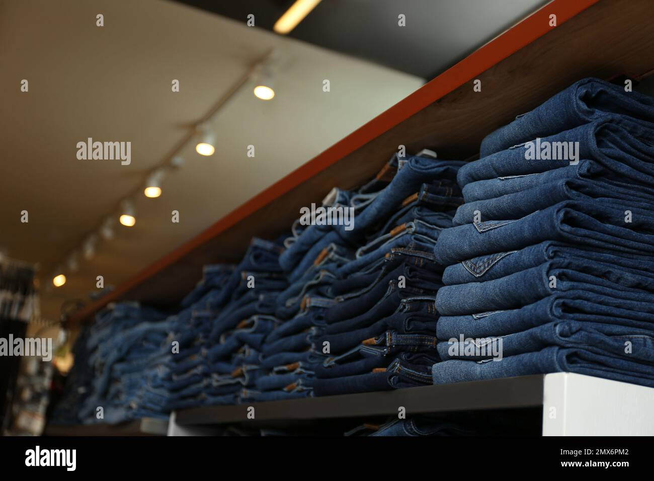 Collection of stylish jeans on shelf in shop Stock Photo - Alamy