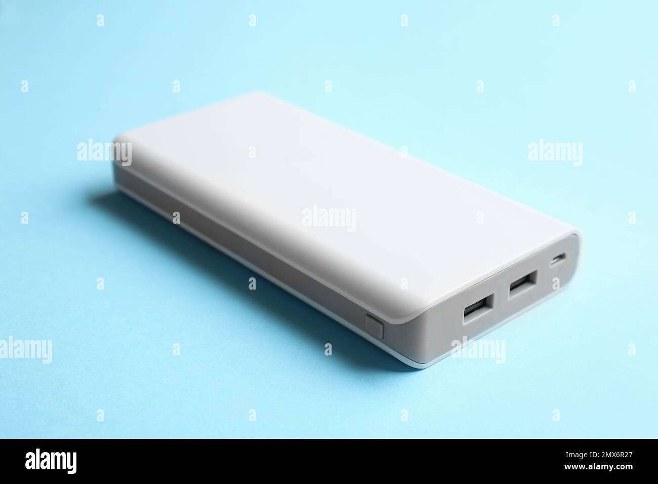 Modern external portable charger on light blue background, closeup ...