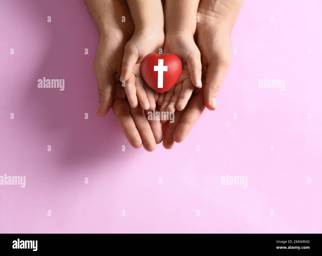 Mother and her child holding heart with cross symbol on pink background ...