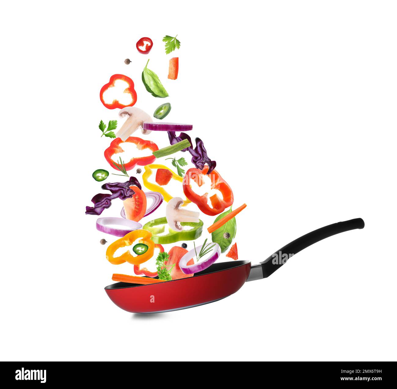 Different vegetables falling into frying pan on white background ...